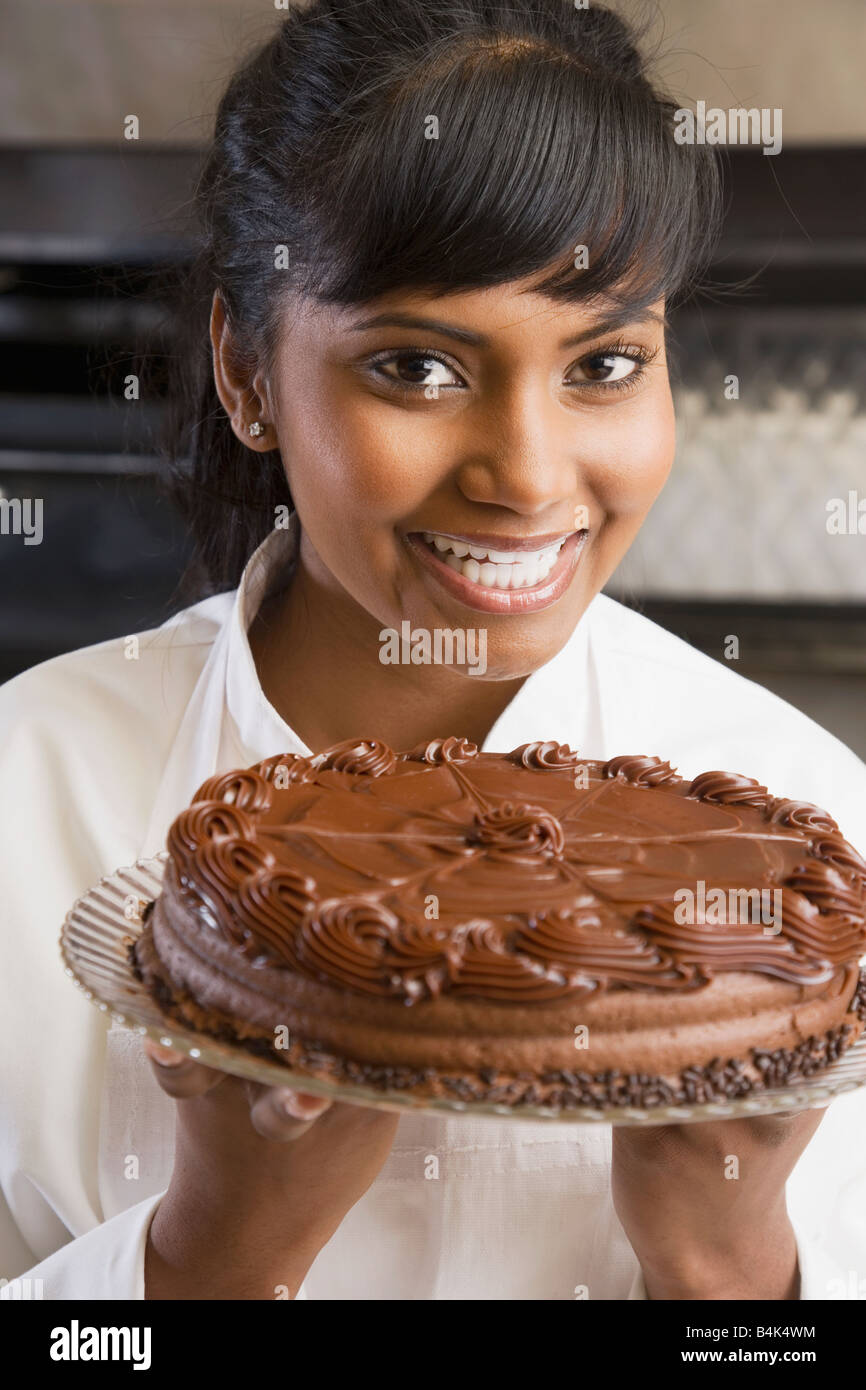Mixed Race female pastry chef holding cake Stock Photo - Alamy