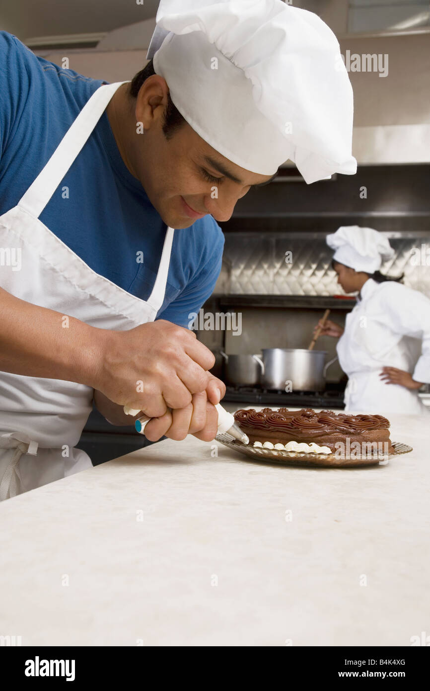 Hispanic male pastry chef decorating cake Stock Photo - Alamy