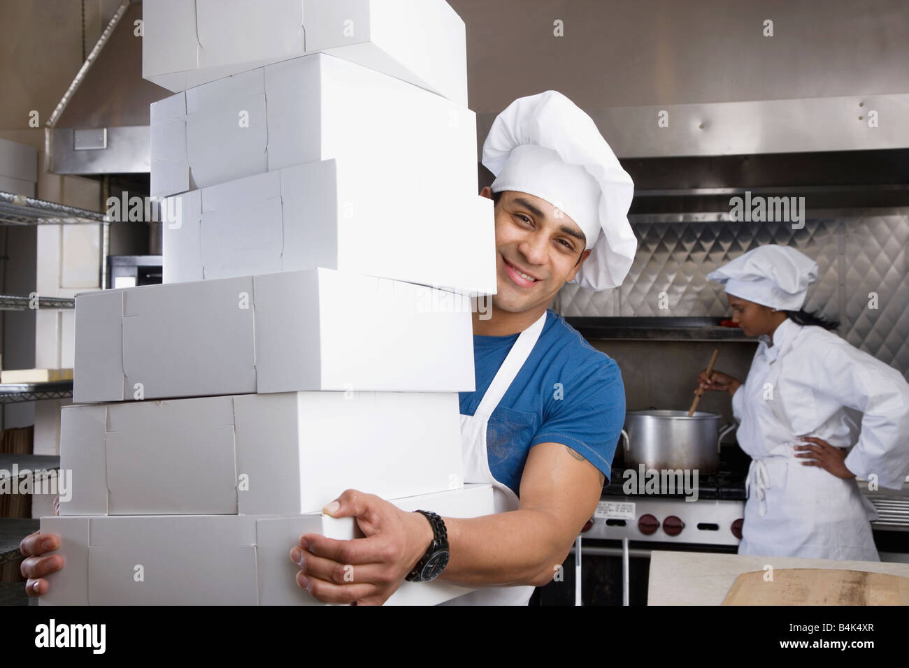 Hispanic male pastry chef carrying stack of boxes Stock Photo - Alamy
