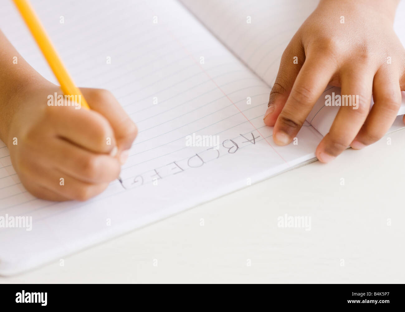 Mixed race girl writing ABC’s Stock Photo - Alamy