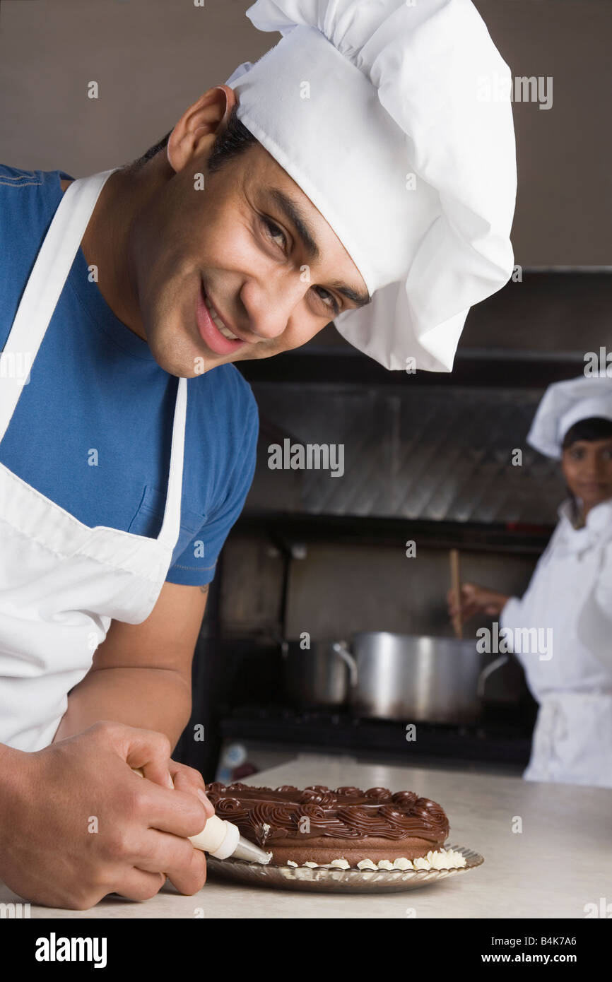 Hispanic male pastry chef decorating cake Stock Photo - Alamy