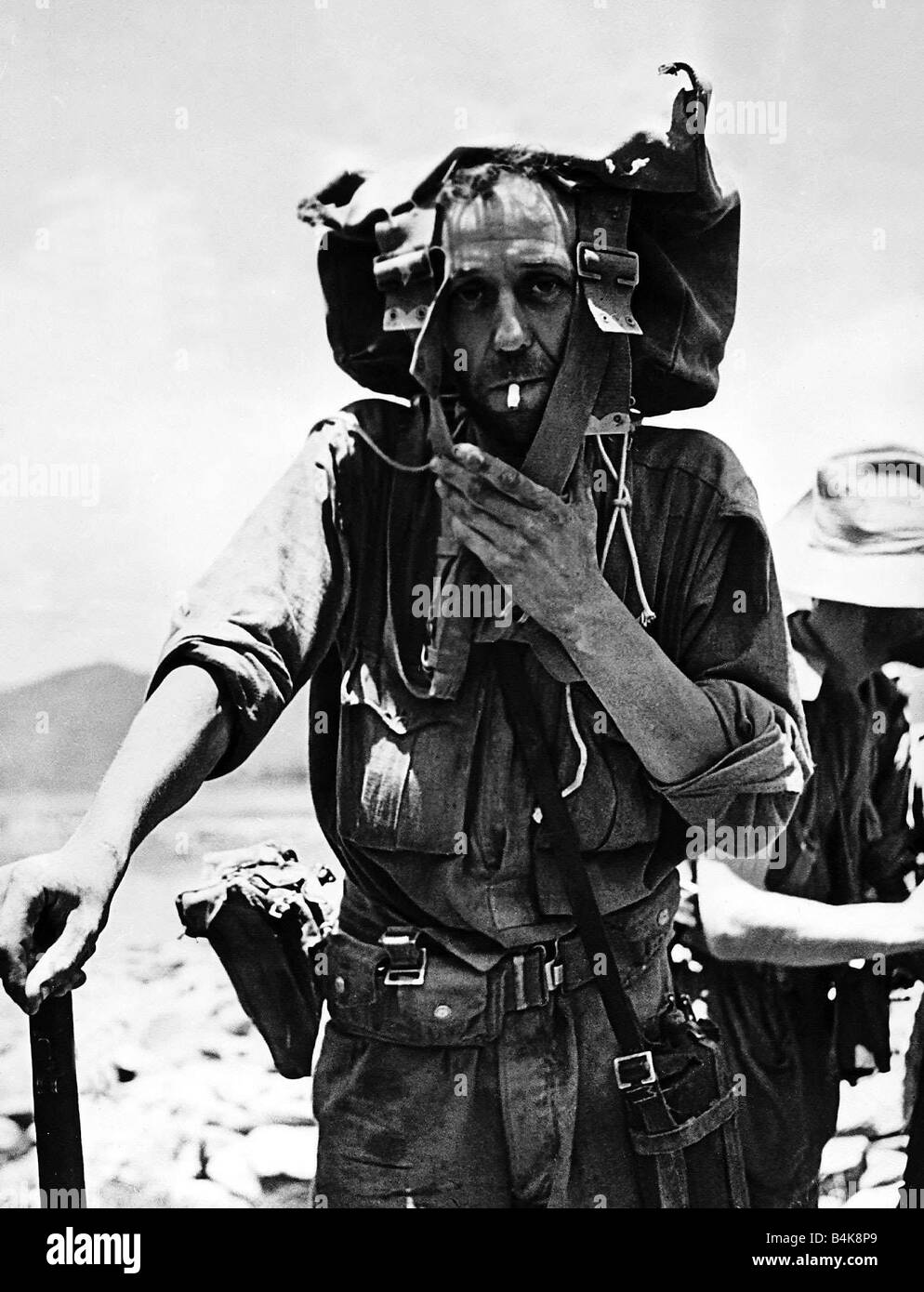 A British soldier uses his backpack to shade his head from the sun as ...