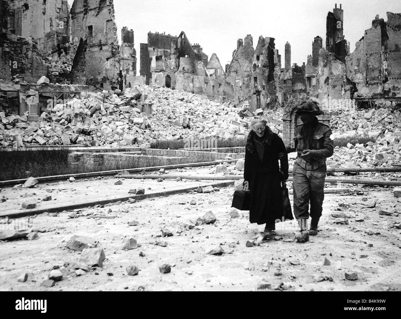 WW2 Invasion of Caen in France A soldier helps an elderly woman through ...