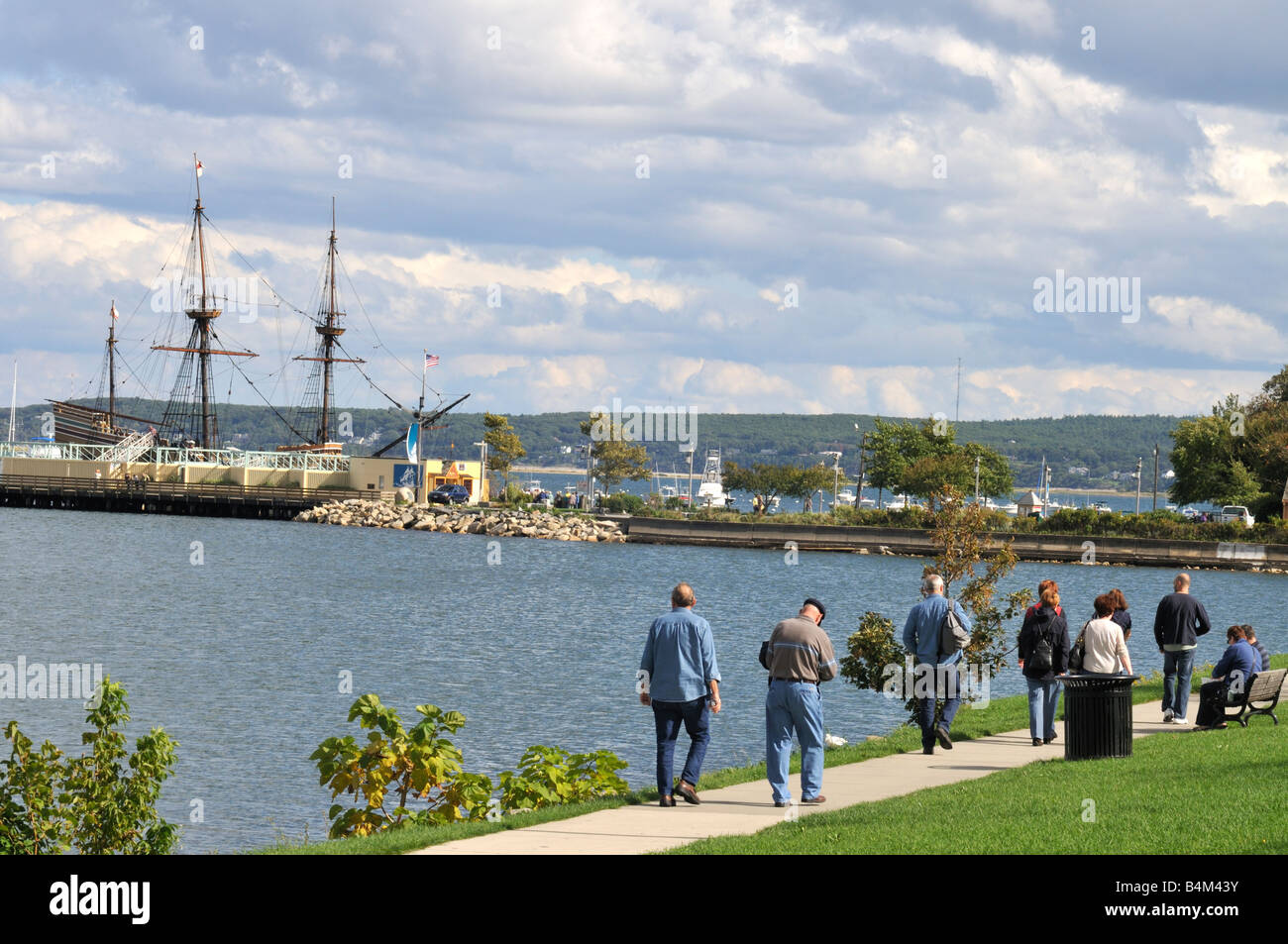 People walking path along Plymouth Harbor, MA, USA with the repilca of ...