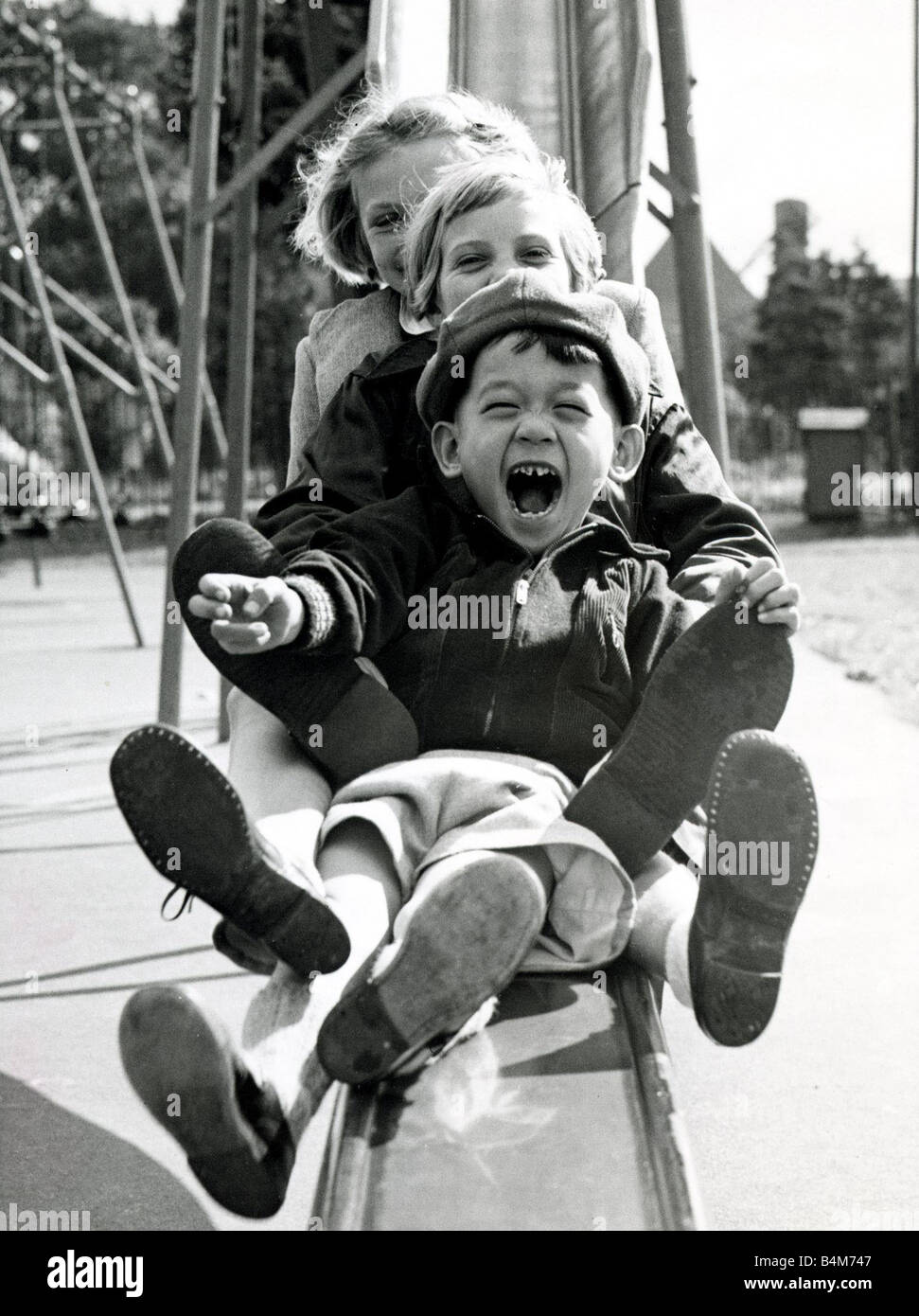 Children playing smiling going down a slide chute September 1955 at ...