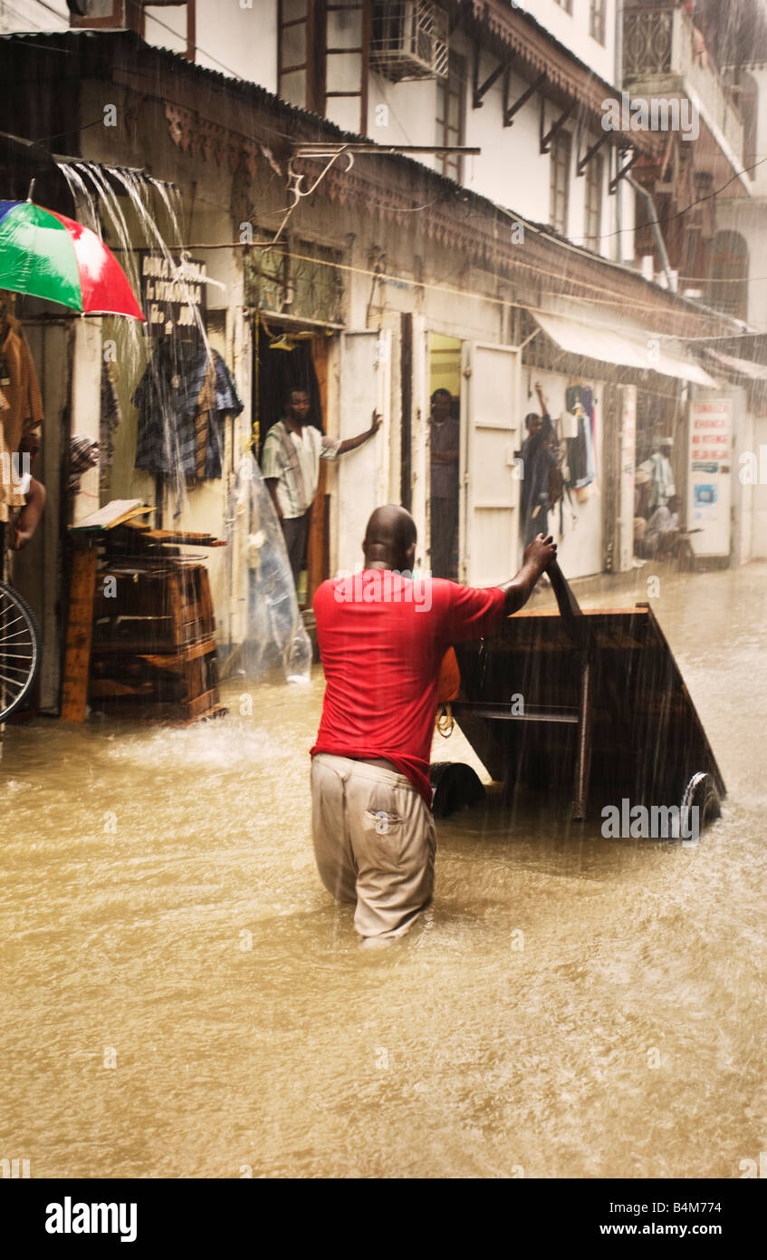 Man with transport cart caught in monsoon seasonal rains in flooded old ...