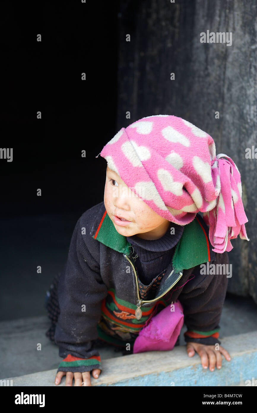 India, Sikkim. Small Indian girl in pink hat crawling out of door Stock ...