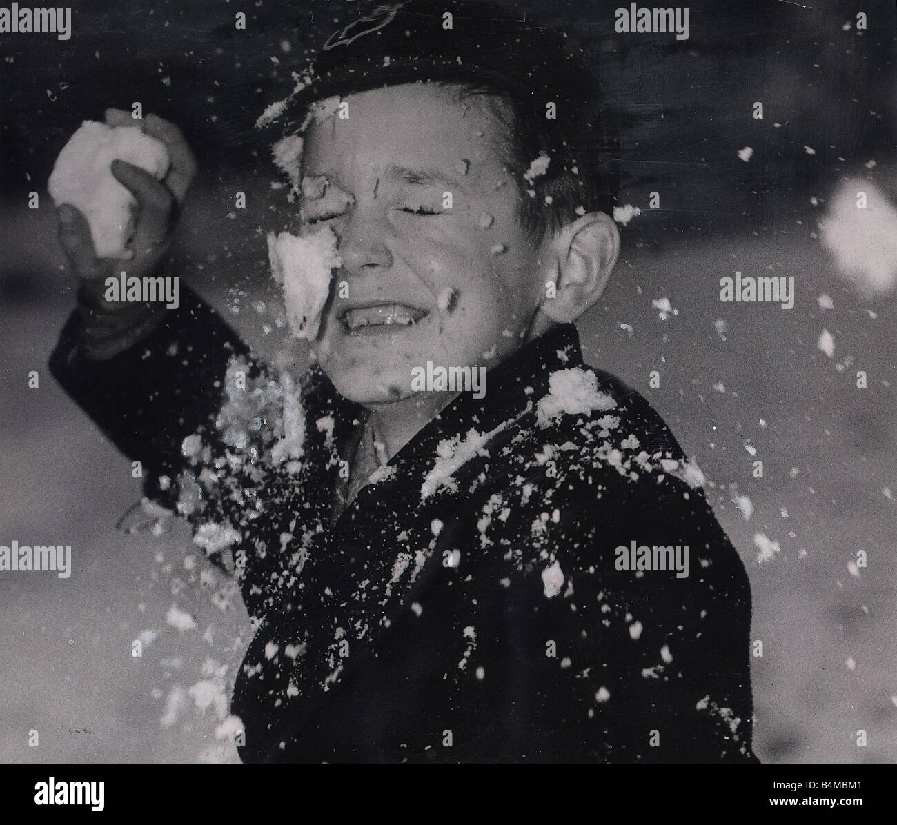 Boy throwing a snowball and being hit by snow thrown back at him by his ...