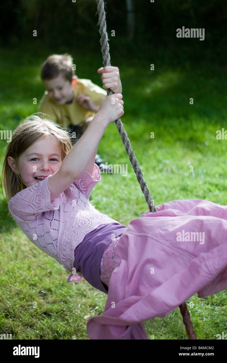 boy pushing girl on a rope swing Stock Photo - Alamy