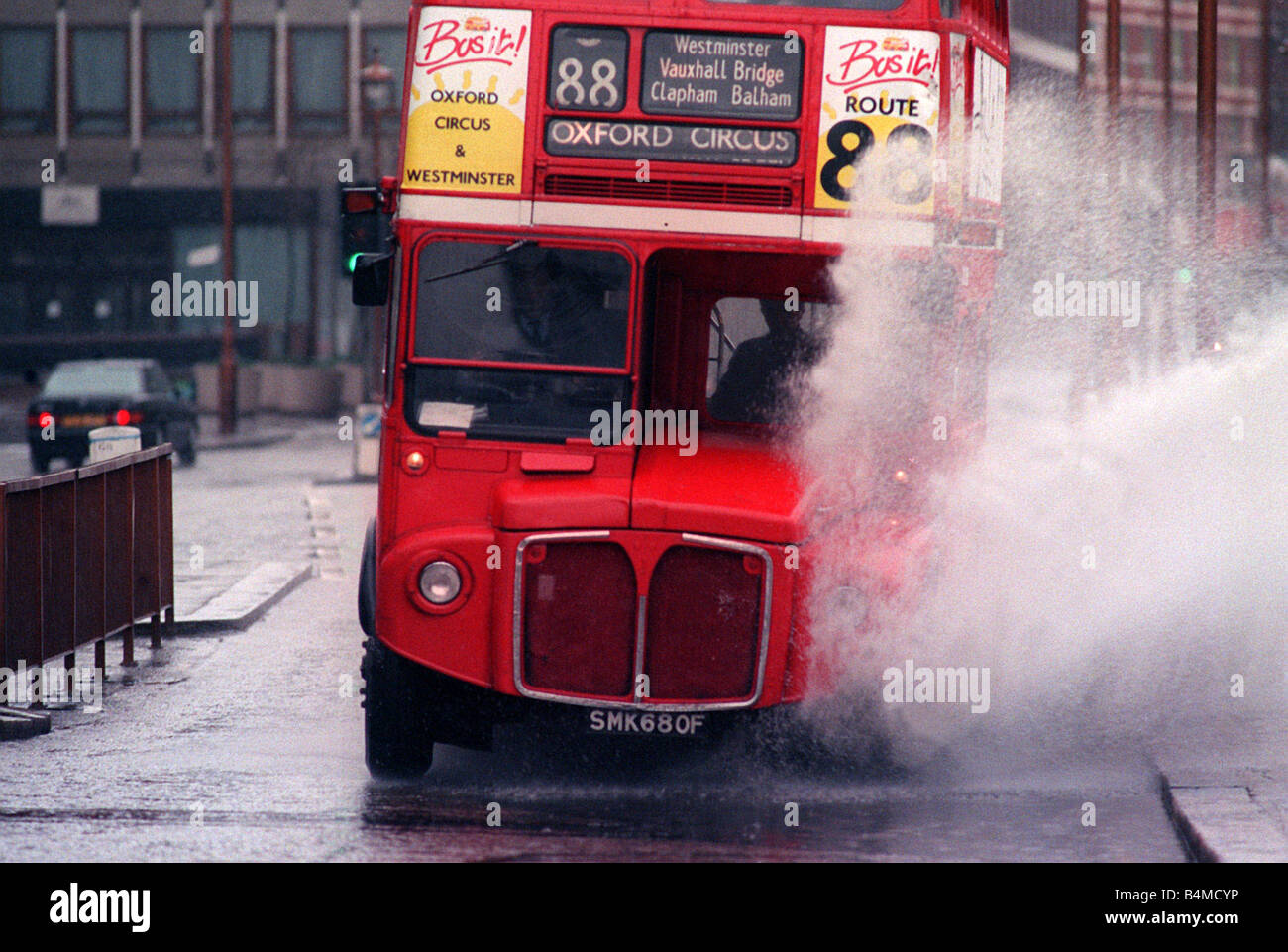 A bus splashing through a large puddle of water after a heavy rainfall ...