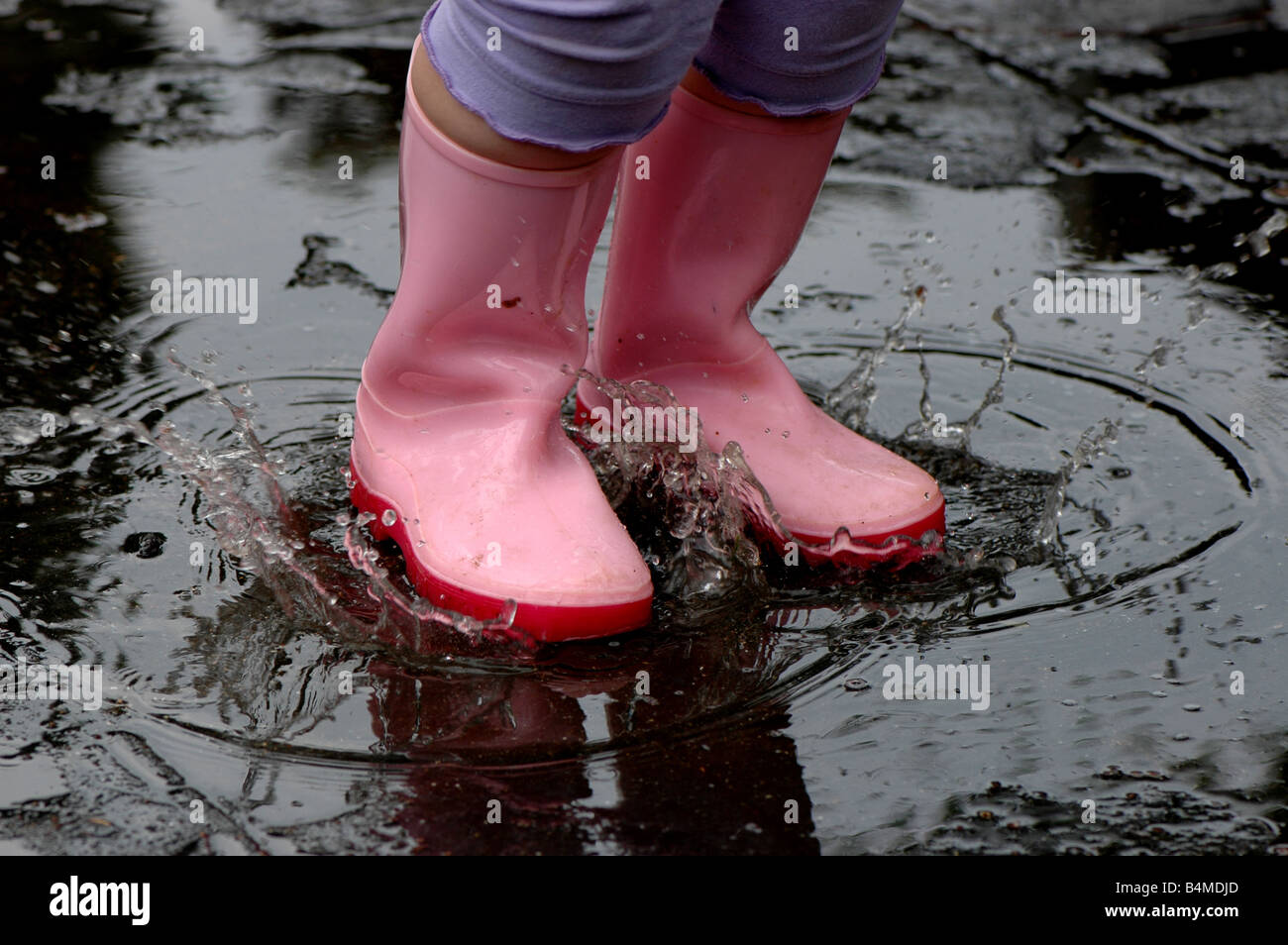 Pink wellington boots splashing in a puddle Stock Photo - Alamy