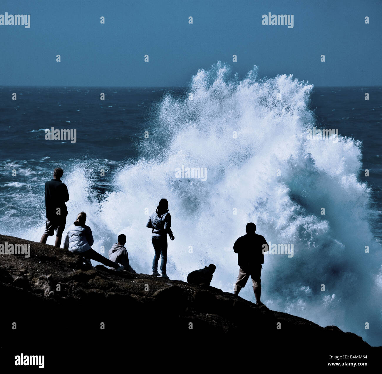 People watching as a powerful wave crashes onto rocks Stock Photo - Alamy