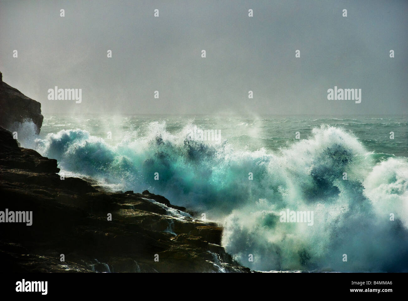 A powerful wave crashing onto rocks at Sennen in Cornwall Stock Photo ...