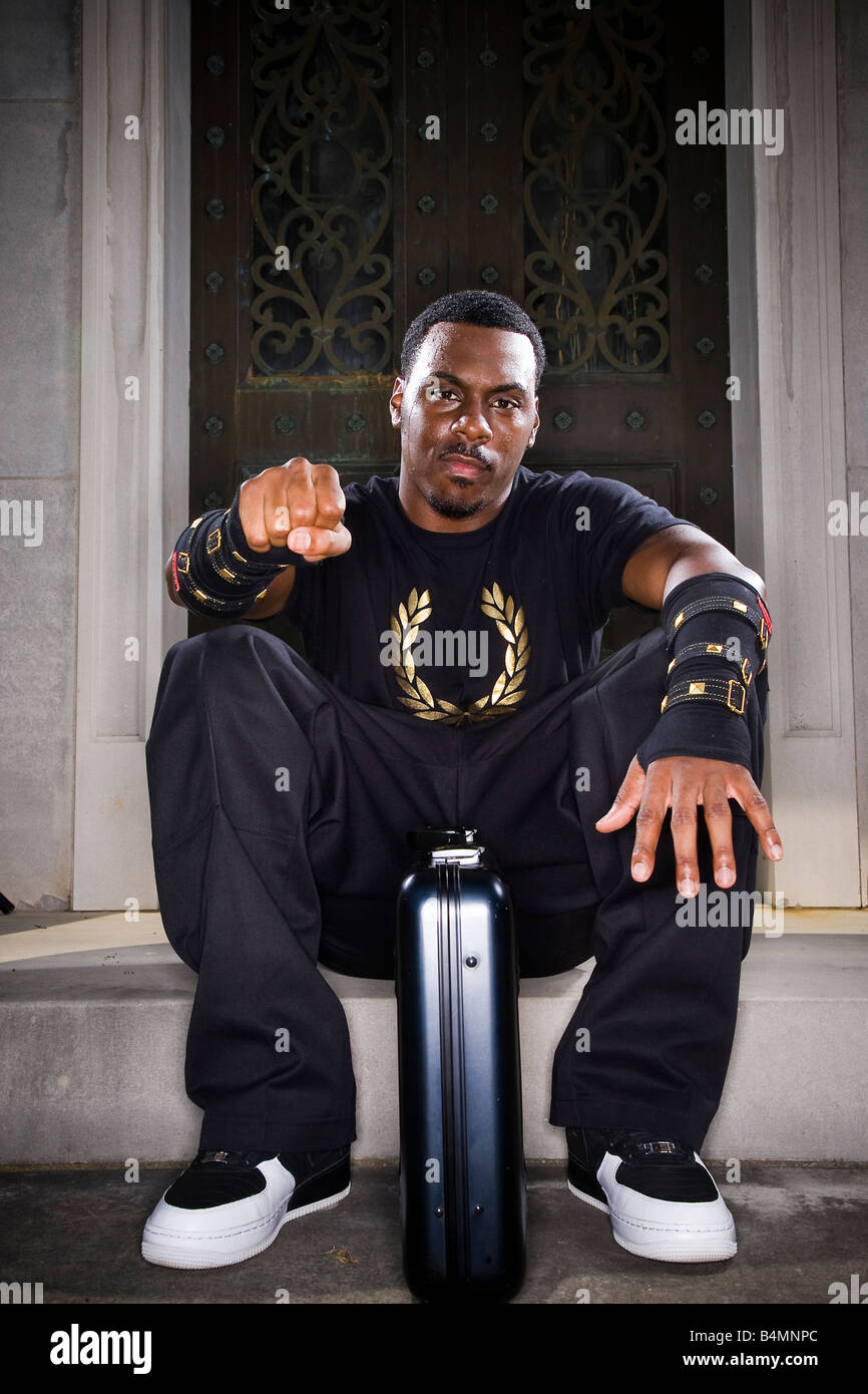 Stylish black man sitting on a marble stoop in front of an iron door ...