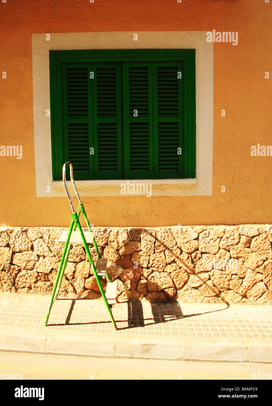 A window with newly painted green shutters,with a green step ladder in ...