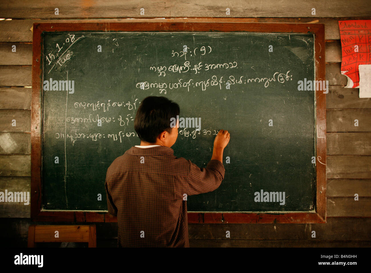 A teacher writes on the chalkboard at the refugee school Approximately ...