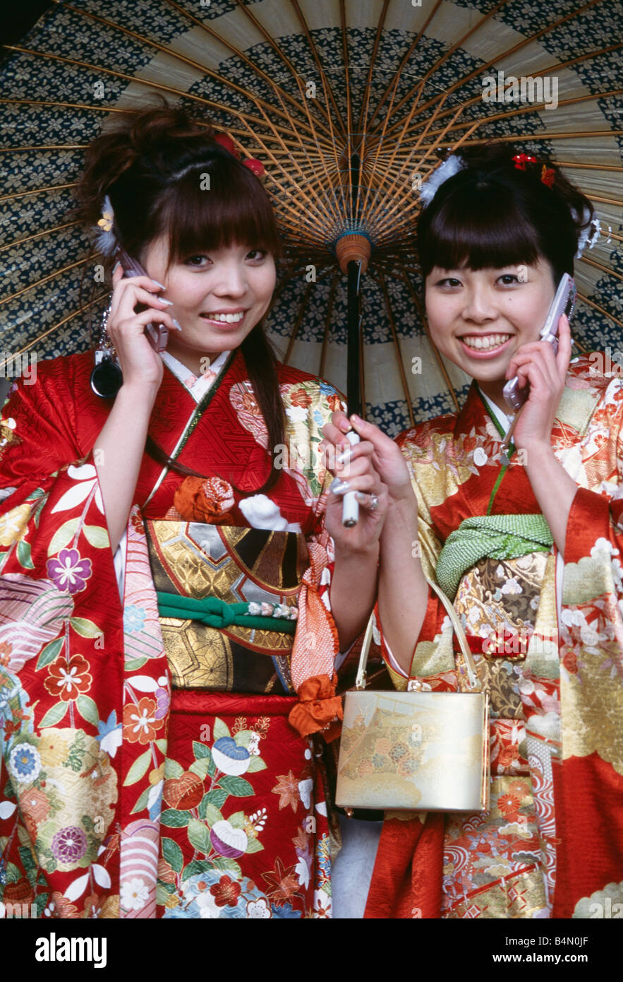 2 Japanese Girls with umbrella on Coming of Age Day using their cell ...