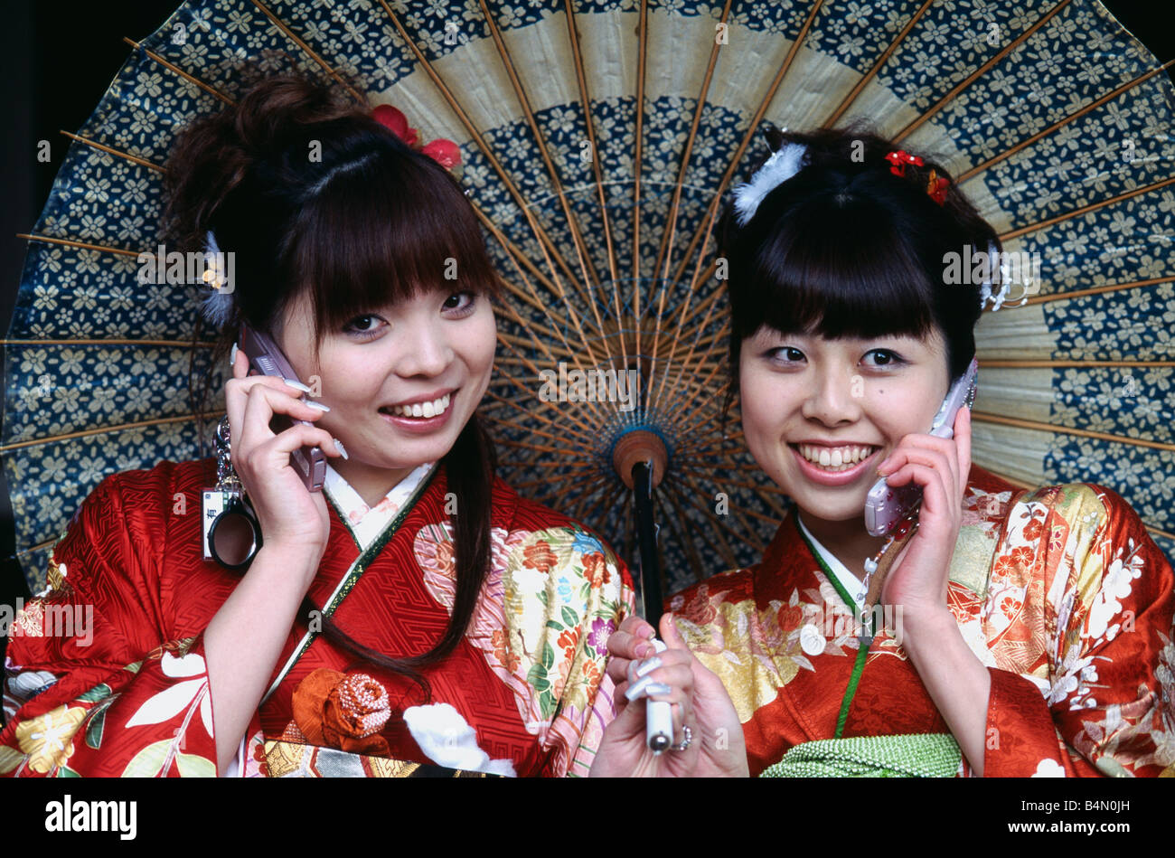 2 Japanese Girls with umbrella on Coming of Age Day using their cell ...