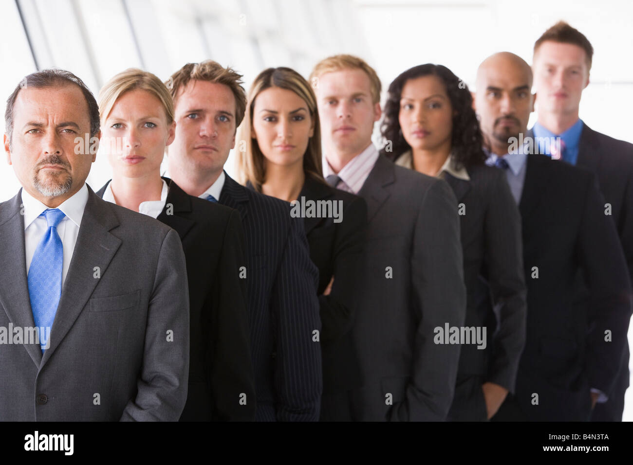 Group of co-workers standing in office space smiling (high key/depth of ...