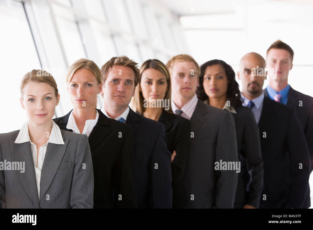 Group of co-workers standing in office space smiling (high key/depth of ...