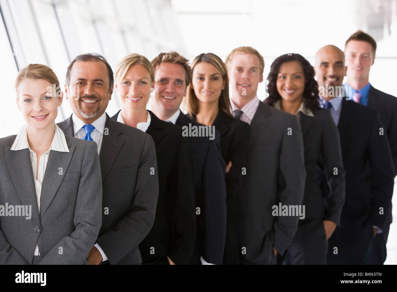 Group of co-workers standing in office space smiling (high key/depth of ...