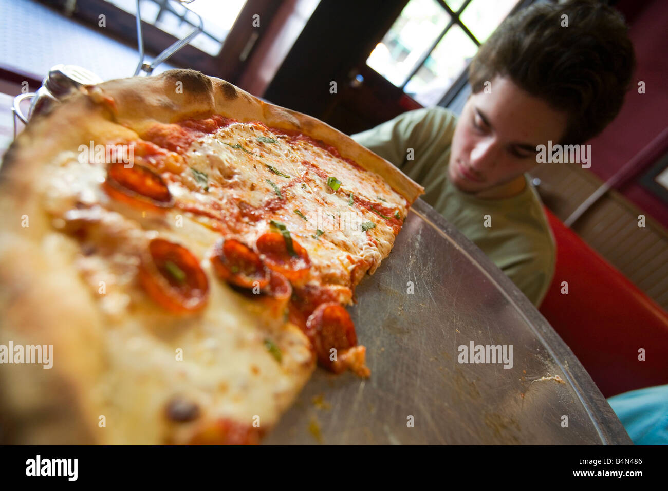 Young man eating pizza in a restaurant Stock Photo - Alamy
