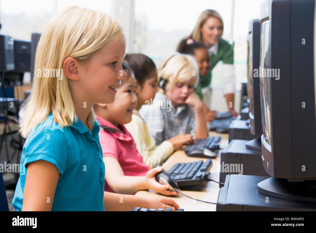 Children at computer terminals with teacher in background (depth of ...