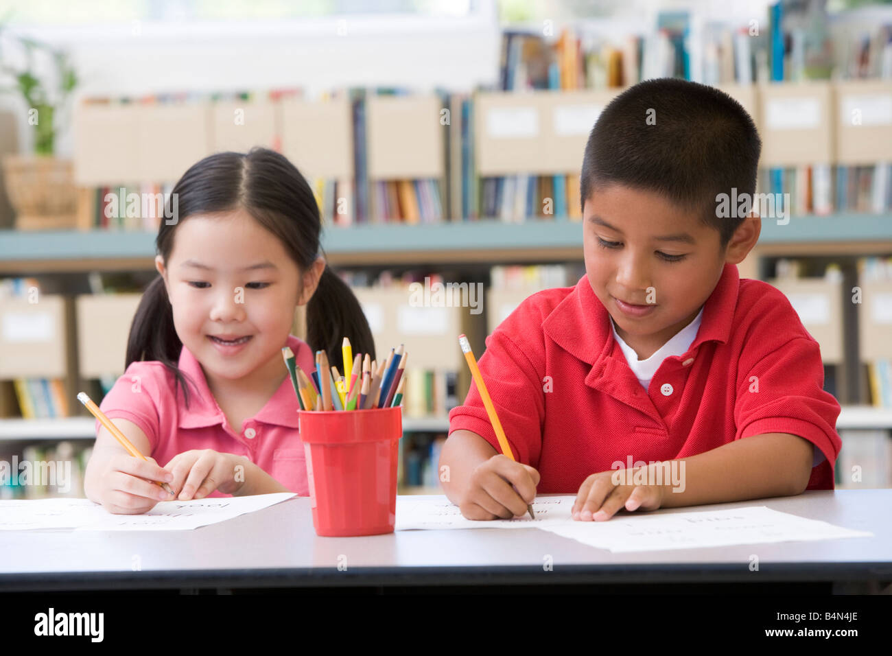 Two students in class writing Stock Photo - Alamy
