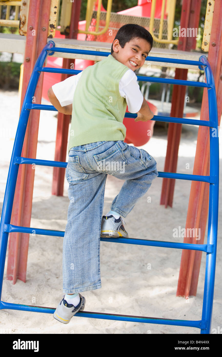 Young boy climbing on playground structure smiling (selective focus ...