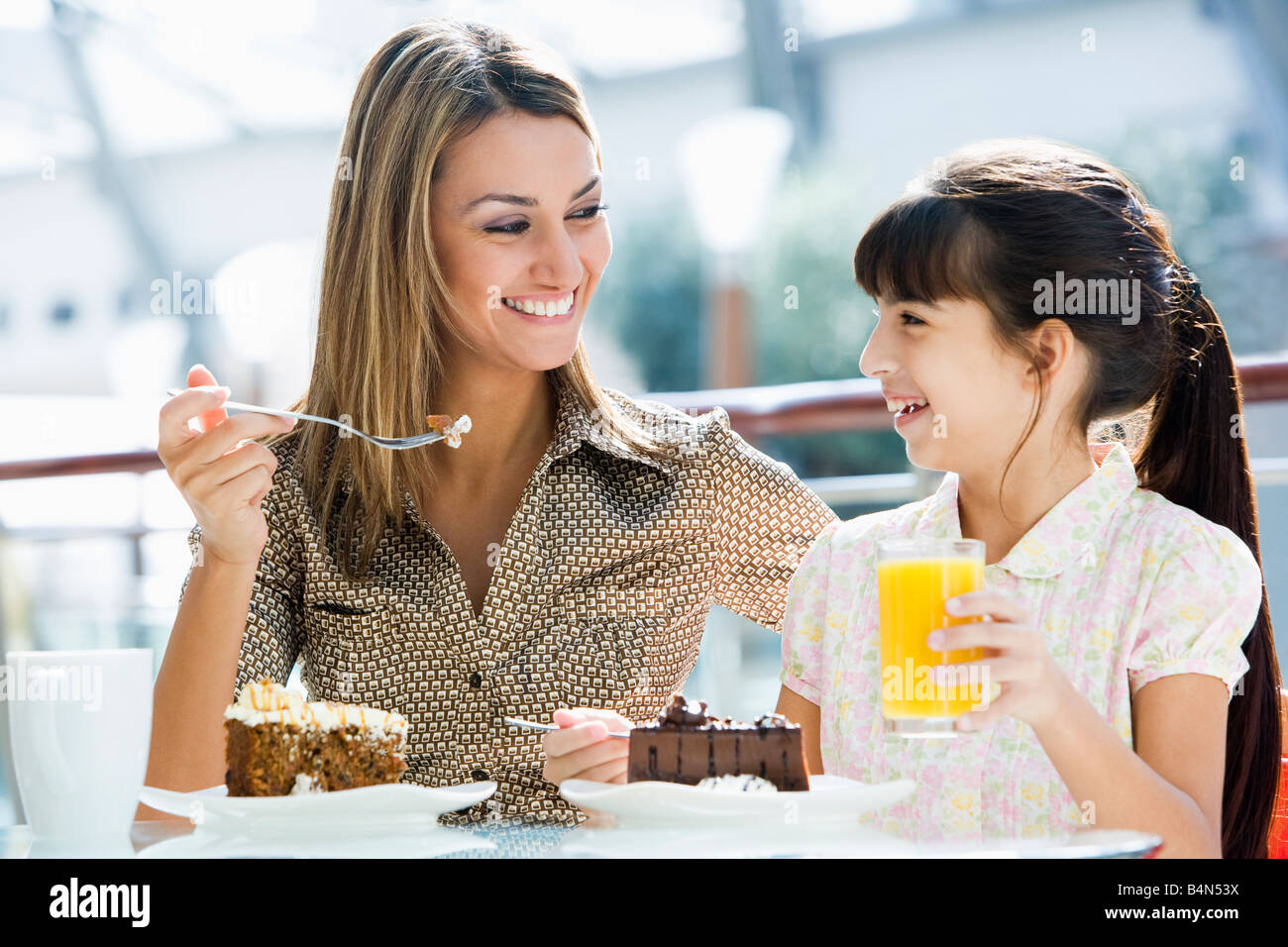 Mother at restaurant with daughter eating dessert and smiling ...