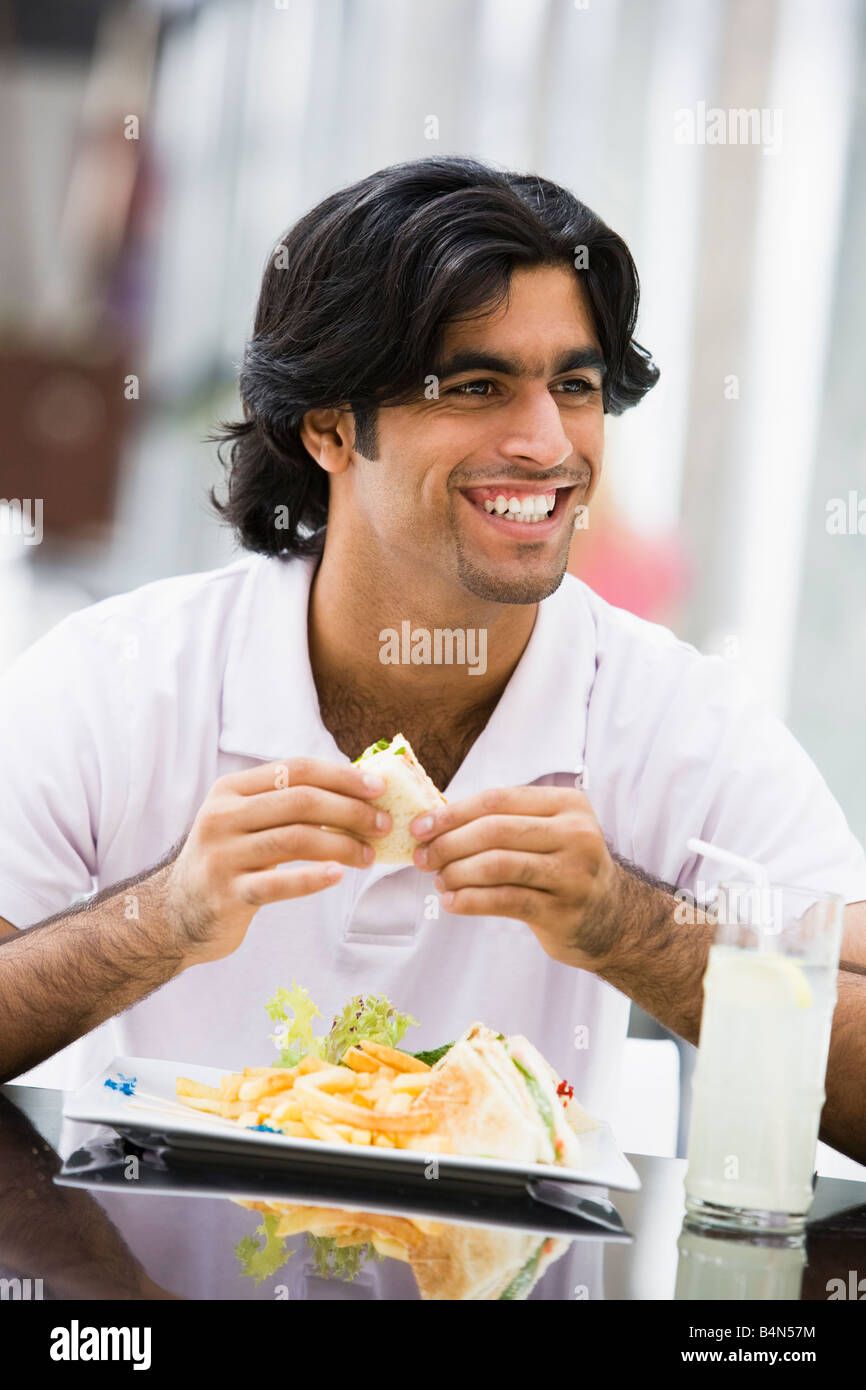 Man at restaurant eating sandwich and smiling (selective focus Stock ...