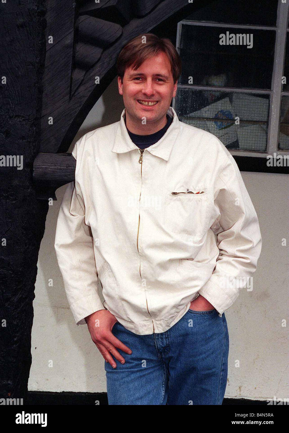 Gary Webster actor standing in archway white jacket denims hand in ...