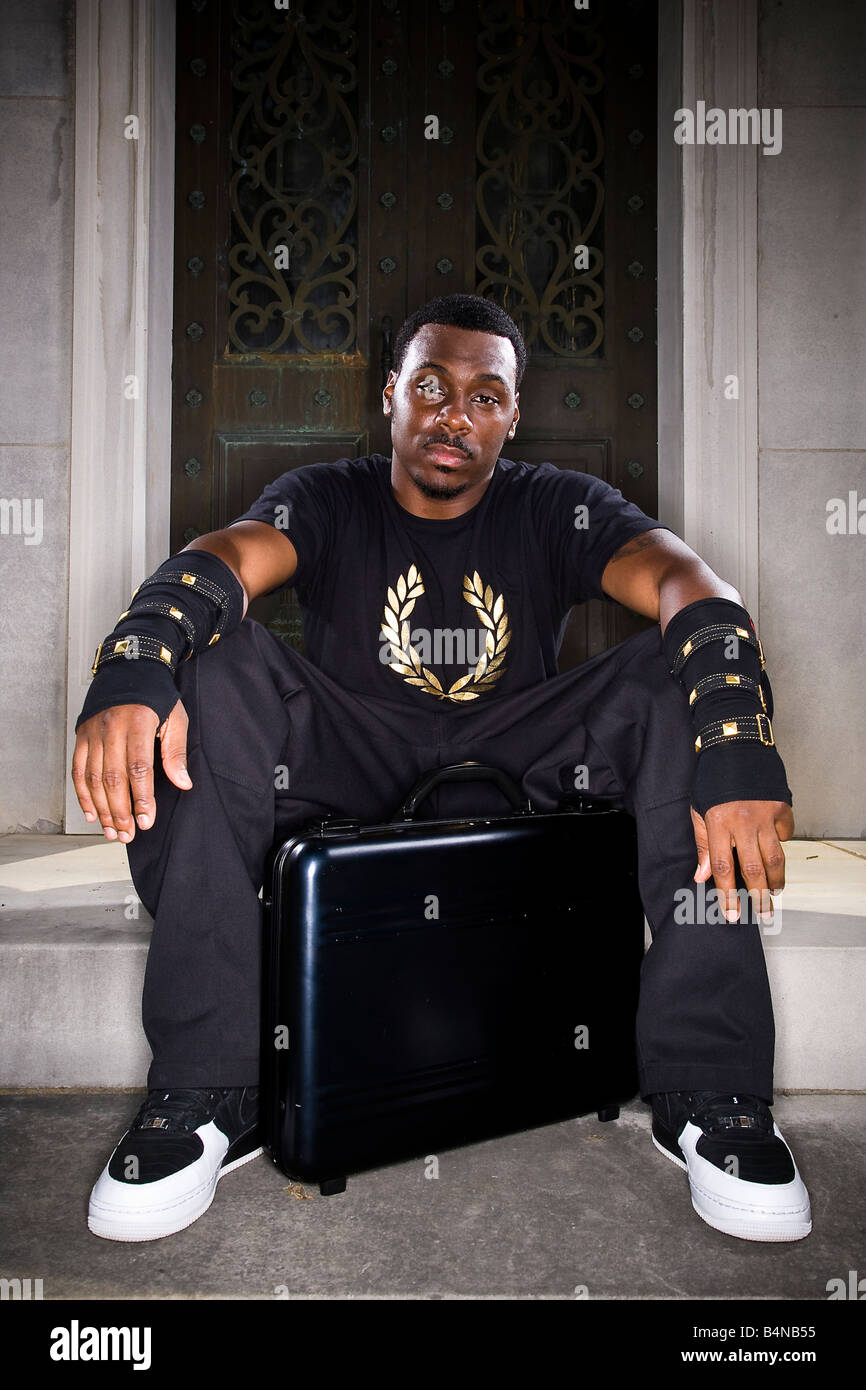 Stylish black man sitting on a stoop with a briefcase between his legs ...