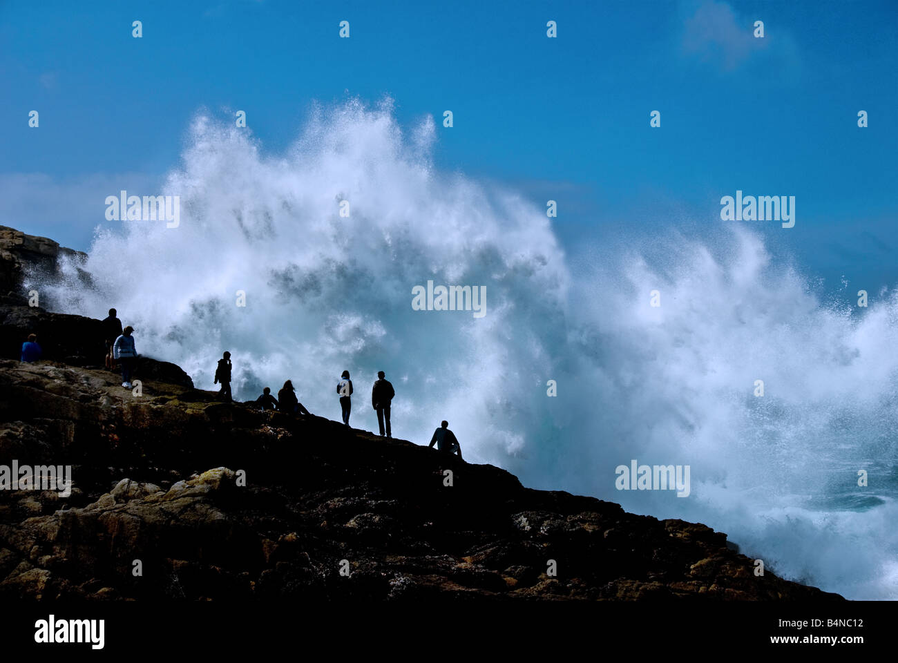 People watching as a powerful wave crashes onto rocks Stock Photo - Alamy