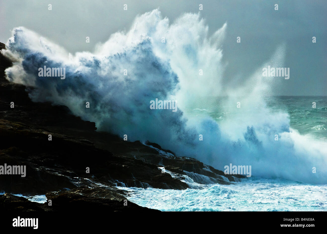 A powerful wave crashing onto rocks. Photo by Gordon Scammell Stock ...