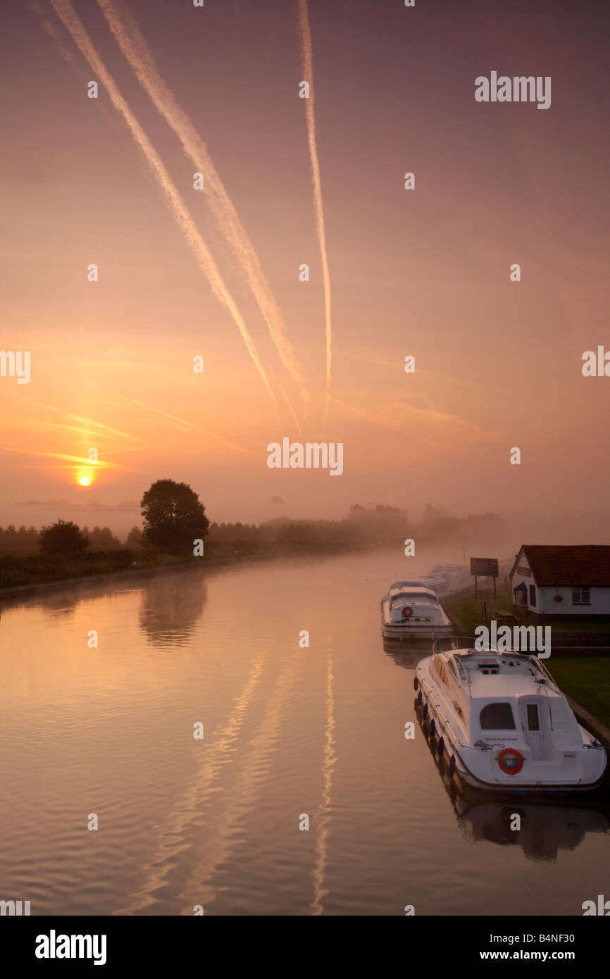 The River Bure at sunrise on a misty morning viewed from Acle Bridge on ...