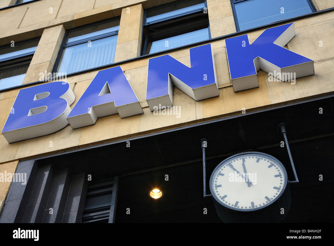 BANK sign on a building and a clock showing five to twelve Stock Photo ...