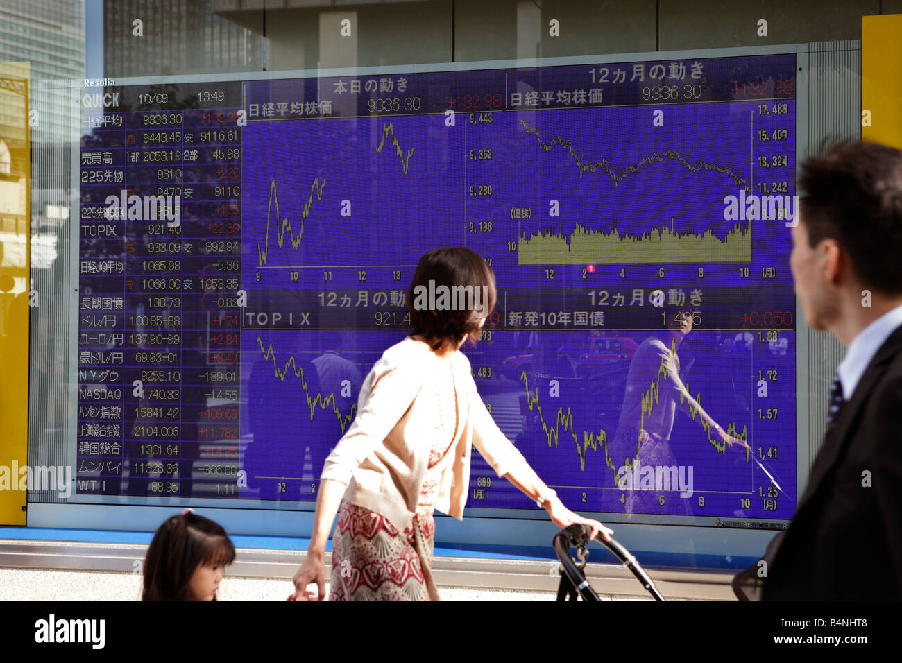 A young mother views a bank stocks and shares monitor screen showing ...