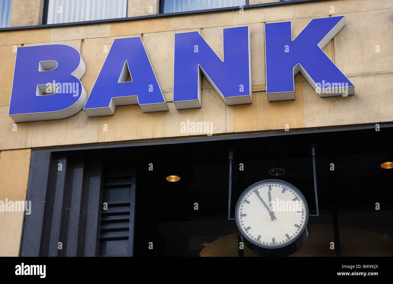 BANK sign on a building and a clock showing five to twelve Stock Photo ...