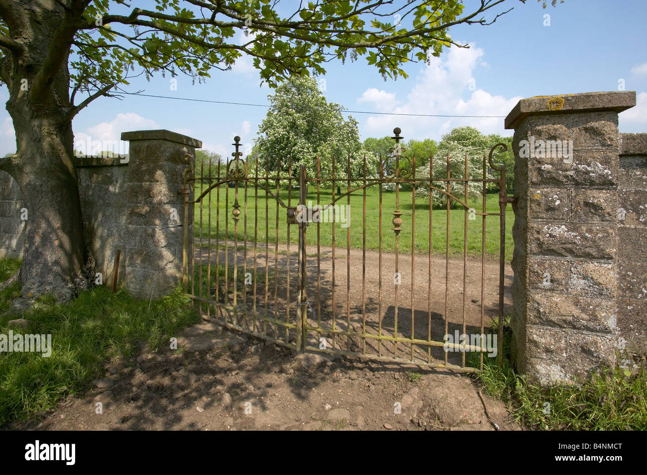 Locked rusty old cast wrought iron double gates with stone piers Stock ...
