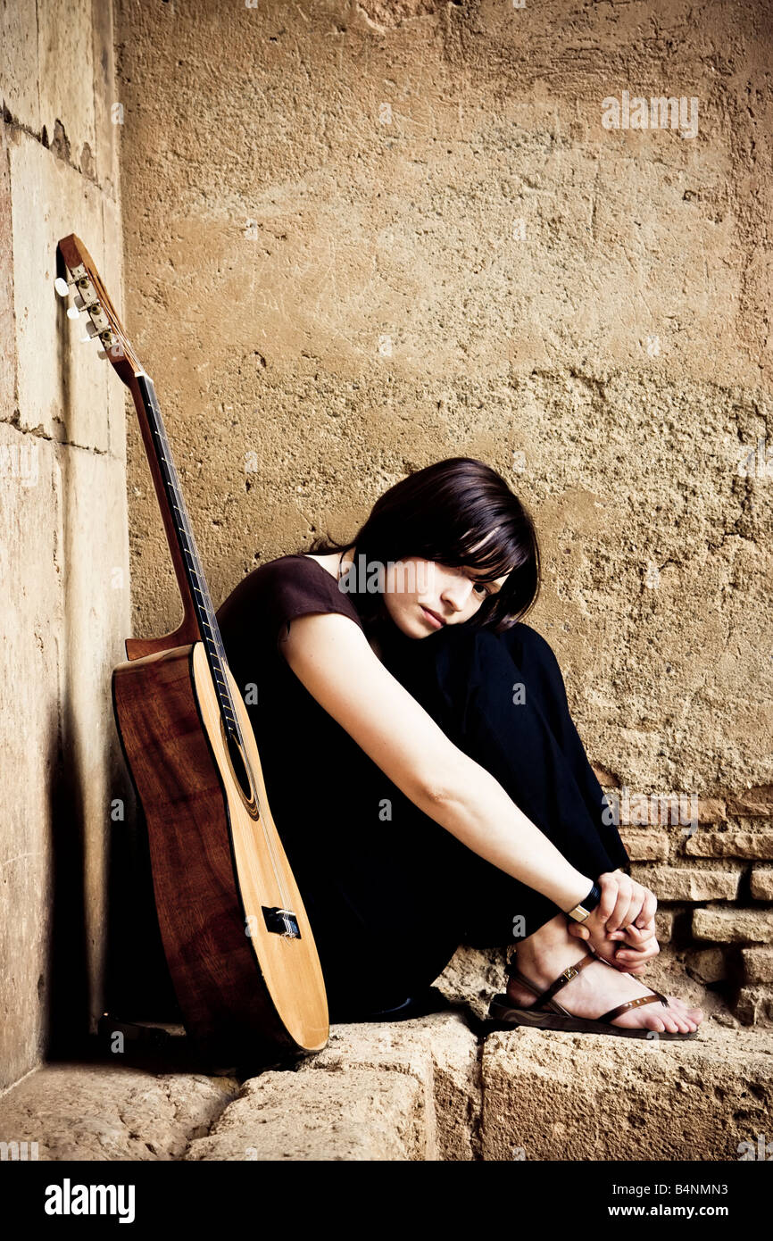 Lone sad guitarist sited in old brickwall Stock Photo - Alamy