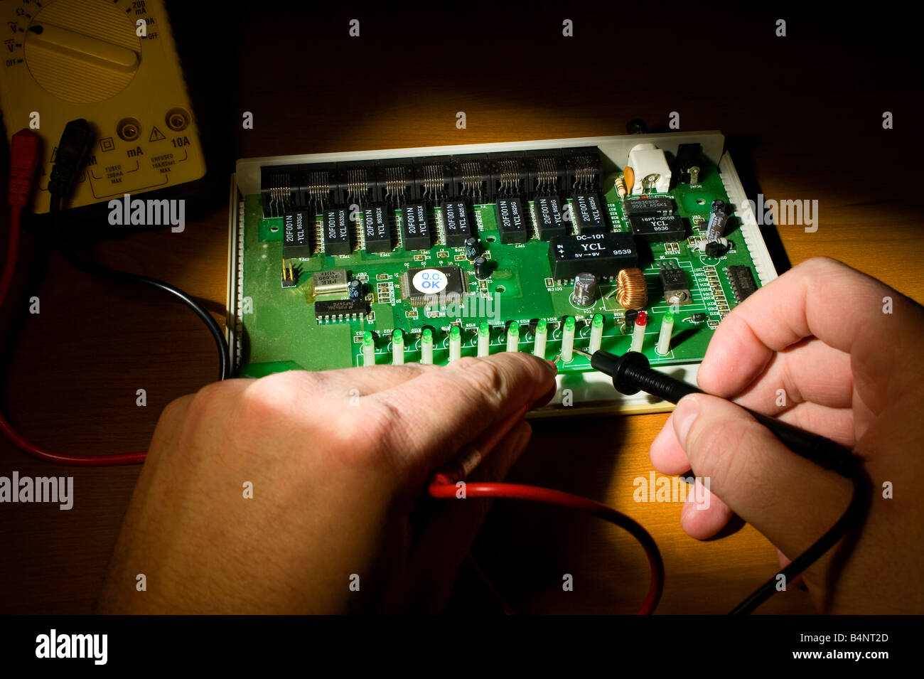 A circuit board is being tested with a multimeter and only the hands of ...