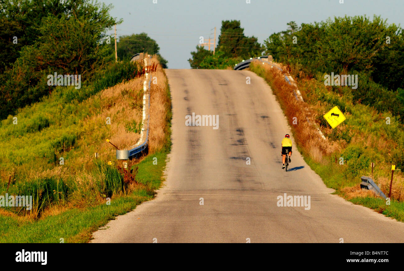 A cyclist riding his bicycle uphill on a rural country road Stock Photo ...
