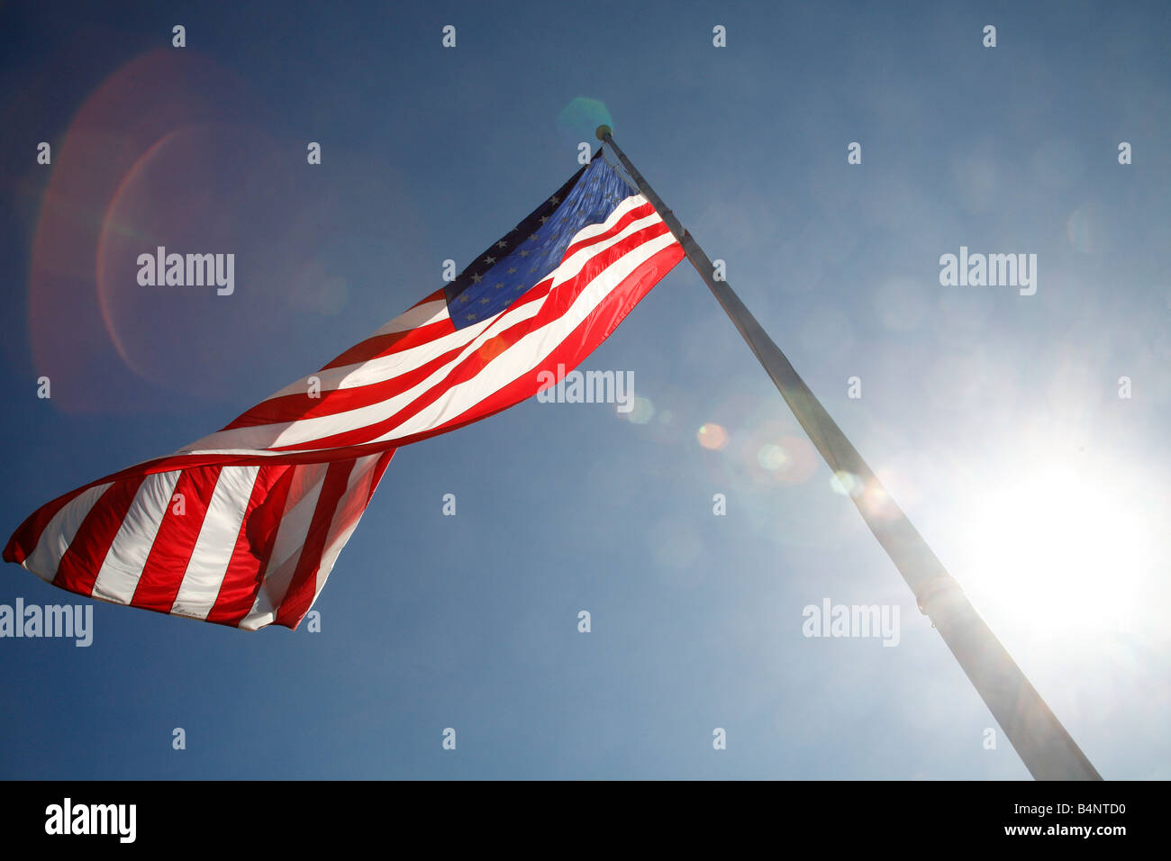 United States Flag against blue sky with lens flare Stock Photo - Alamy