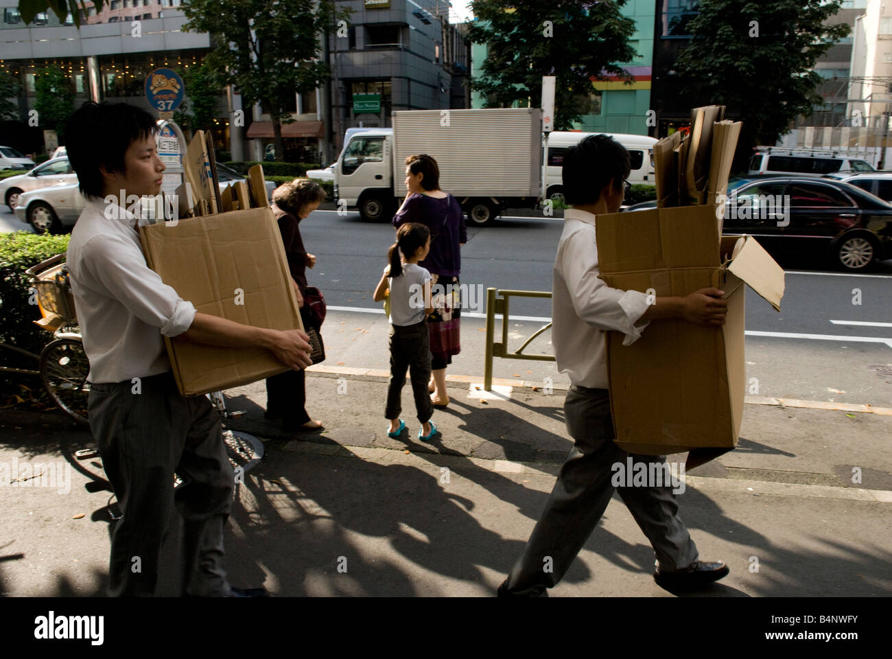 Two men carrying cardboard boxes in Tokyo Stock Photo - Alamy