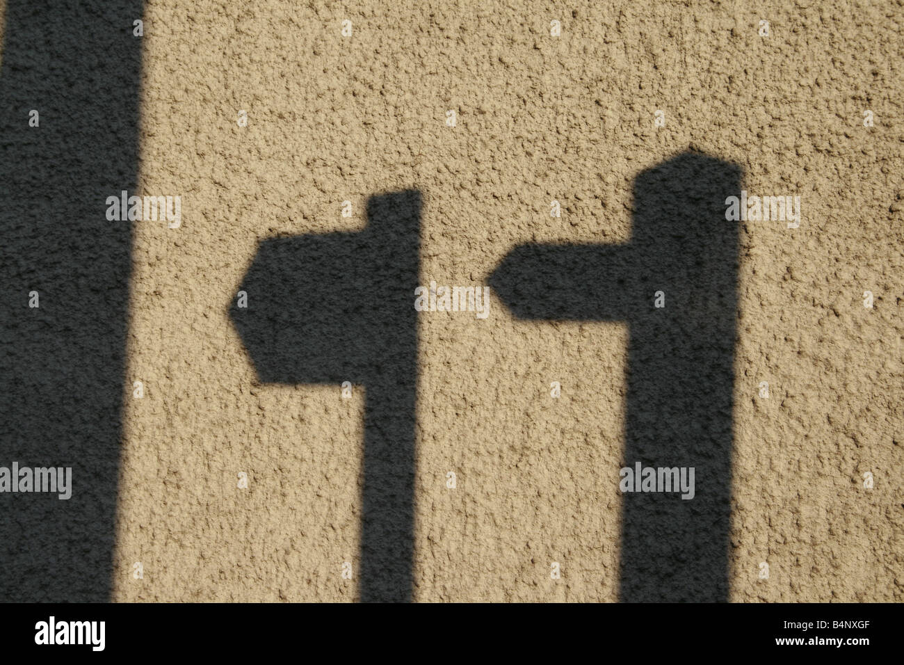 two footpath signs shadow on house wall in sun Stock Photo - Alamy