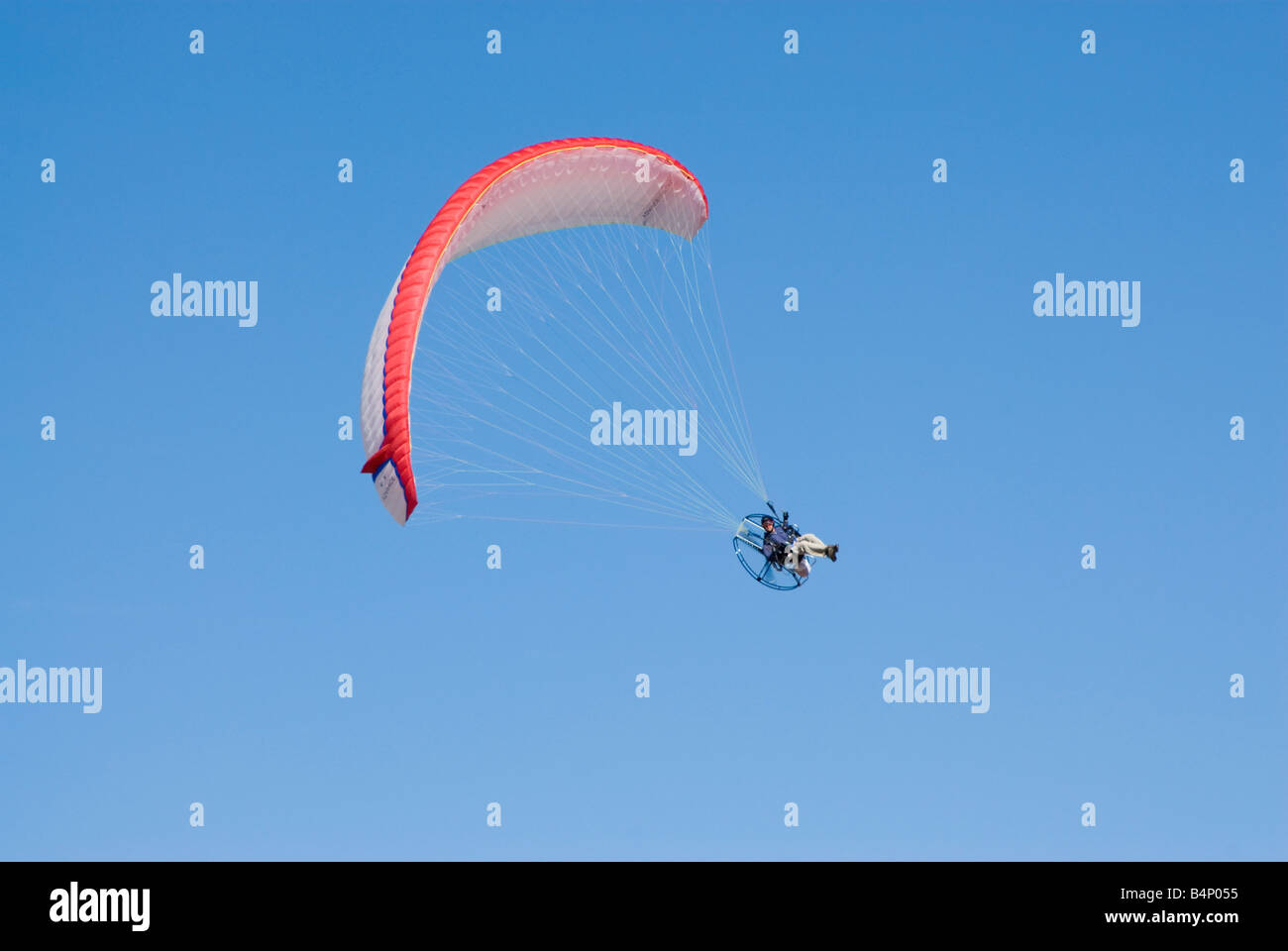 a powered paraglider in flight against a clear blue sky Stock Photo - Alamy