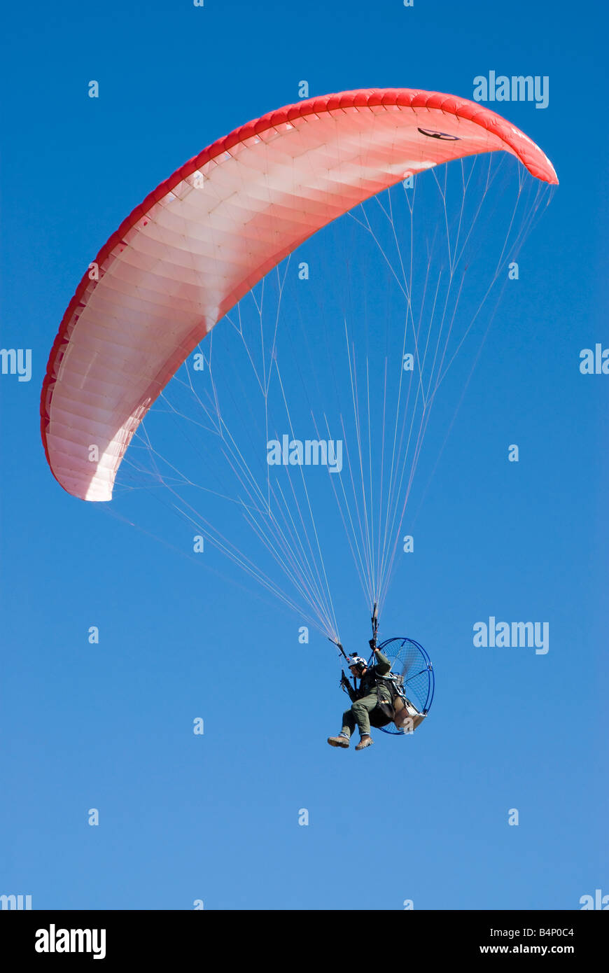 a powered paraglider pilot in flight against a clear blue sky Stock ...