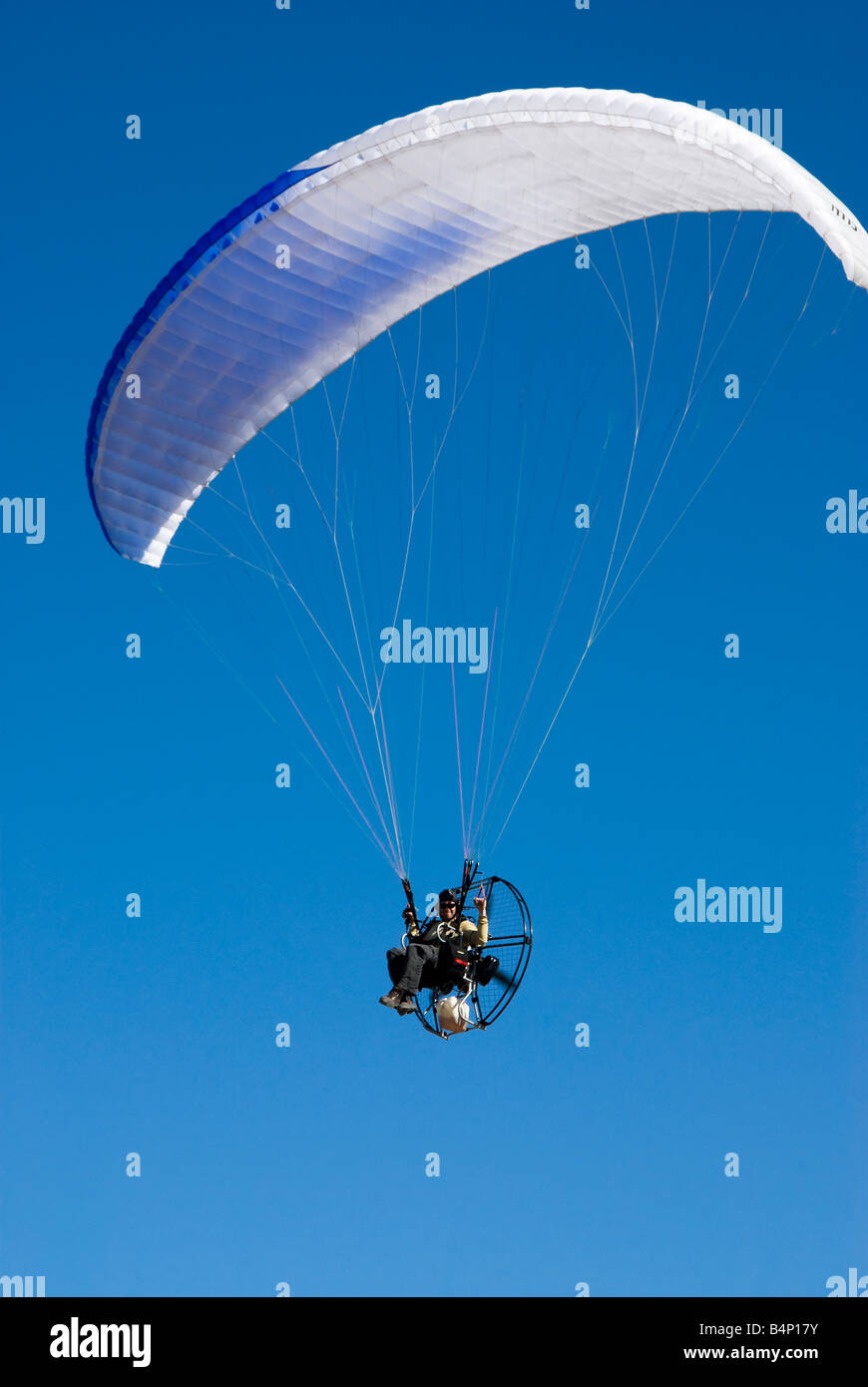 a powered paraglider pilot in flight against a clear blue sky Stock ...