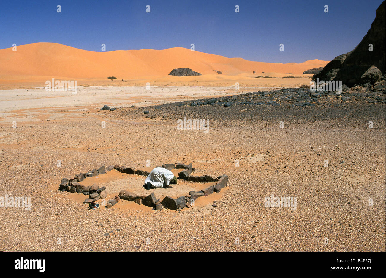 Algeria Djanet Man of Tuareg tribe Praying in desert mosque Sand dunes ...